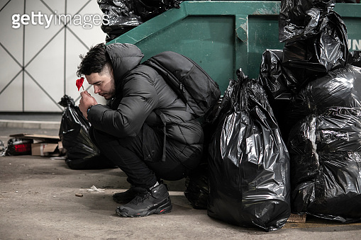 Sad guy with red heart in his hands sitiing text to the trash cans ...