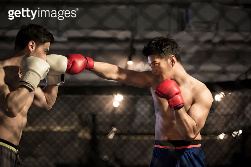 Young male boxer in a boxing match in a boxing pool, attacking and ...