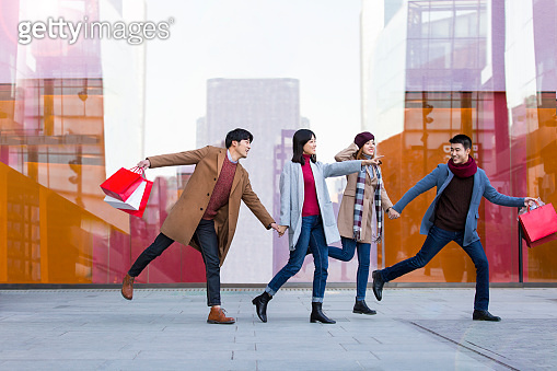 Young East Asian youths snapping up shopping in a busy outdoor shopping ...