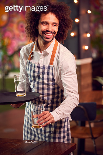 Portrait Of Smiling Male Server Clearing Table In Cool Bar Or Club ...