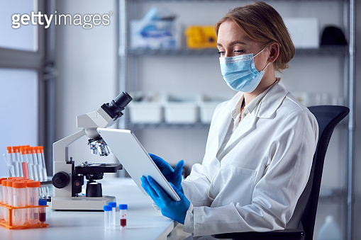 Female Lab Worker Wearing Lab Coat Working On Covid-19 Vaccine With ...