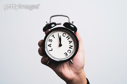 Hand holding black alarm clock which inside last chance wording for ...
