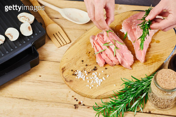Woman cooking meat steak on kitchen. Female chef sprinkles fresh raw ...