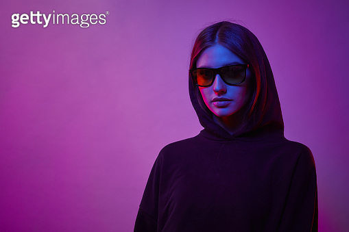 Girl posing in a studio in a trendy neon light. Woman in sunglasses and ...