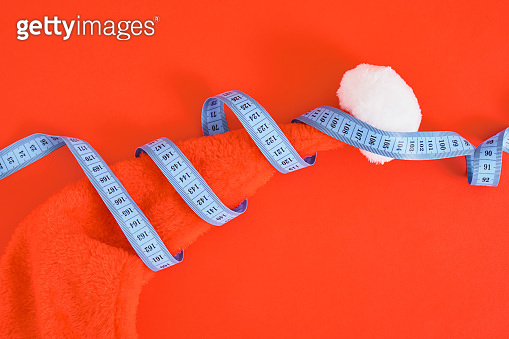 blue measuring tape and red santa claus hat on red background, weight ...