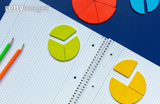 Open notepad, fractions, chart, pencils on a blue background. Close up ...