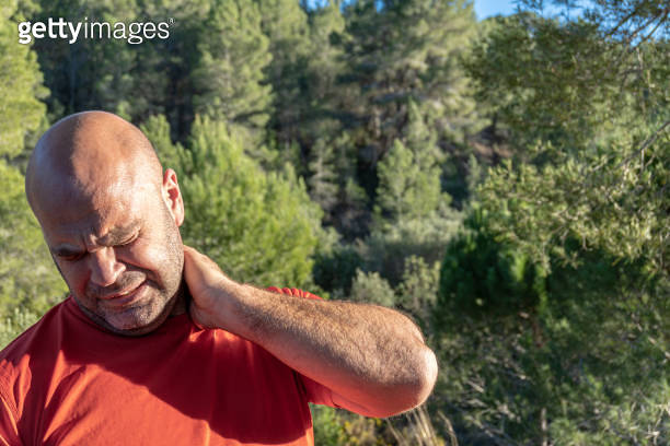 Middle-aged Caucasian man with neck pain, against natural background of ...