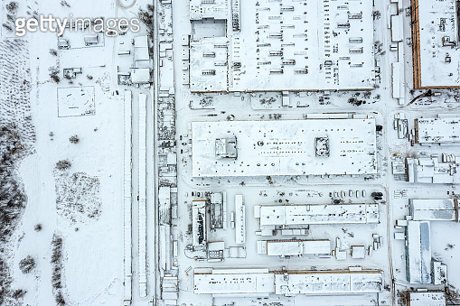 industrial area in winter. factory buildings and warehouses covered ...