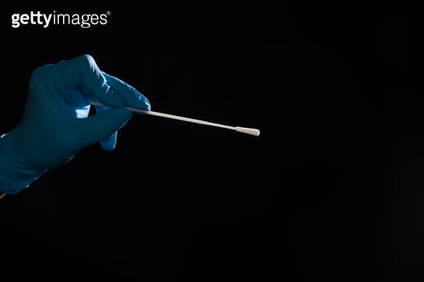 Close up of doctor's hand handling a smear test or swab test in front ...