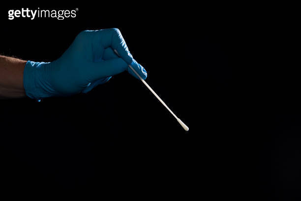Close up of doctor's hand handling a smear test or swab test in front ...