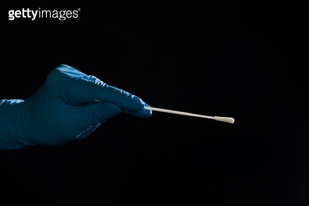 Close up of doctor's hand handling a smear test or swab test in front ...