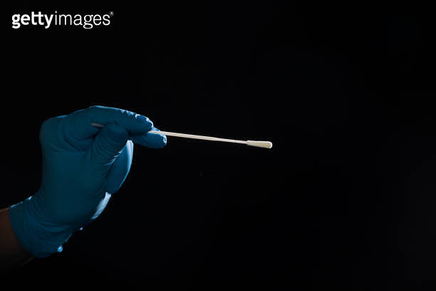 Close up of doctor's hand handling a smear test or swab test in front ...