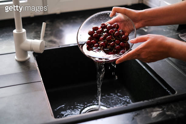woman washing cherries at home under running water to make juice 이미지 ...