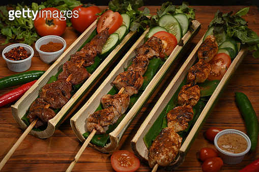 Tasty grilled meat with Sichuan pepper served in bamboo barrel plate and vegetable on rustic ...