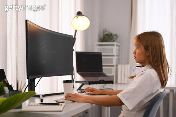 Young female programmer working with coded data on desktop computer in ...