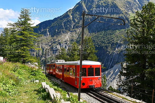 A red tourist train on the rack railway towards the station of ...