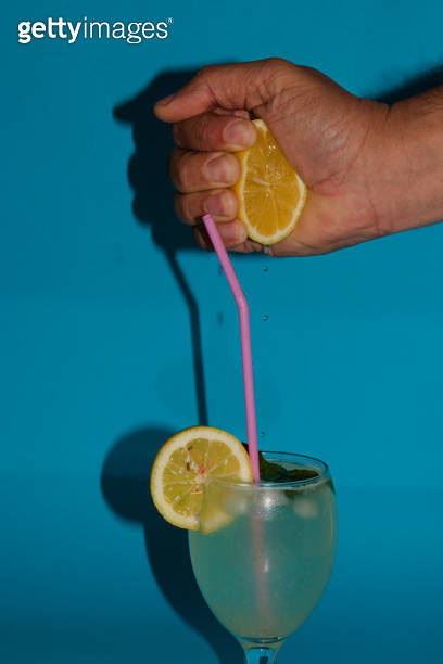 hand squeezing lemons in a beautifully decorated glass of lemonade ...