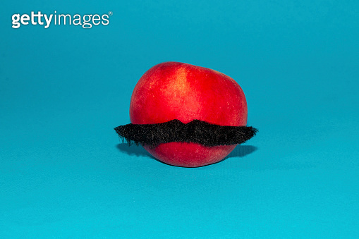 red apple with a mustache isolated on a blue background, a creative ...