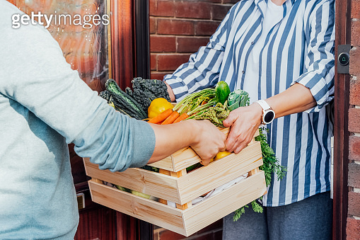 Home fresh food delivery. Woman taking wooden box with vegetables and ...