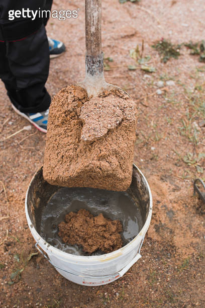 A worker pours sand into a bucket with a shovel - mixing glue 이미지 ...