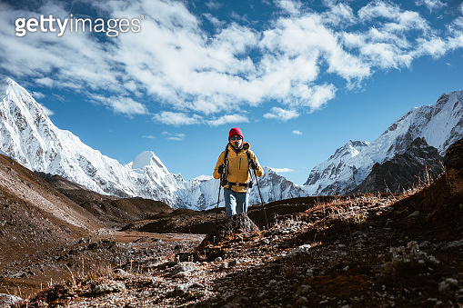 Young tourist walk along high altitude track among snowy and cloudy ...