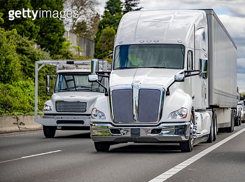 White small and big rigs semi trucks with semi trailers running side by ...