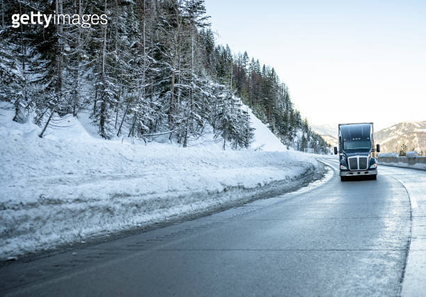 Industrial Black big rig semi truck with semi trailer driving on the ...