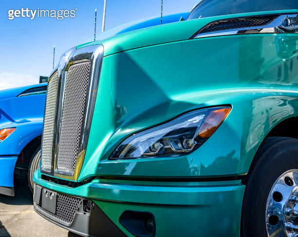 Front part of soft green shiny big rig semi truck tractor cab with ...