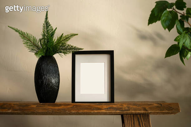 Mockup of black photo frames on a wooden console shelf against a beige ...