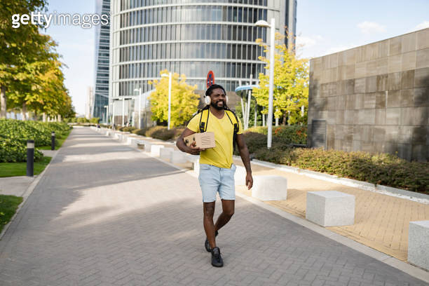 Young African American male delivery man carrying a package and while ...