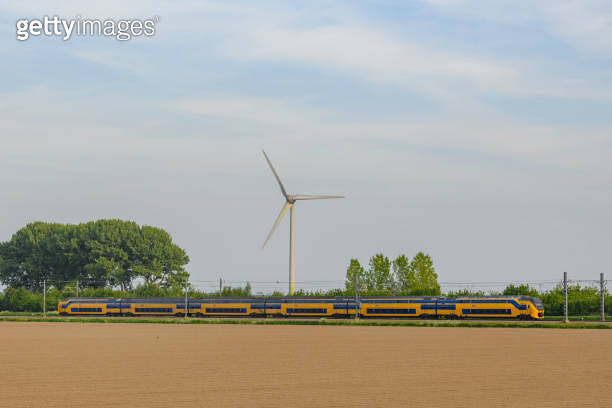 Intercity train of the Dutch Railways driving past wind turbines 이미지 ...
