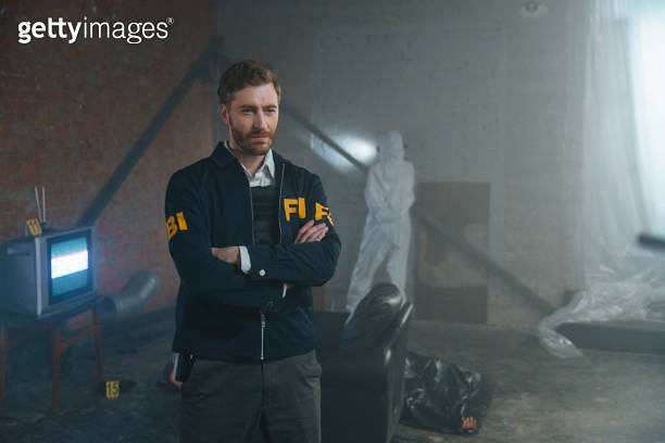 Handsome FBI agent with a beard stands at the crime scene at the den of ...