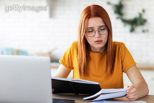 Online learning, portrait of focused beautiful red-haired young female ...
