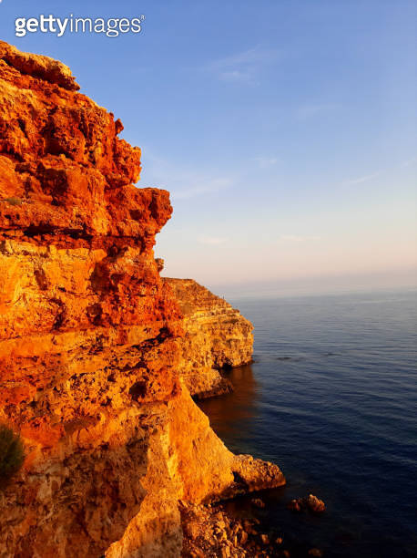 A mountain cliff at the coastline stunningly lightened by the sunset ...