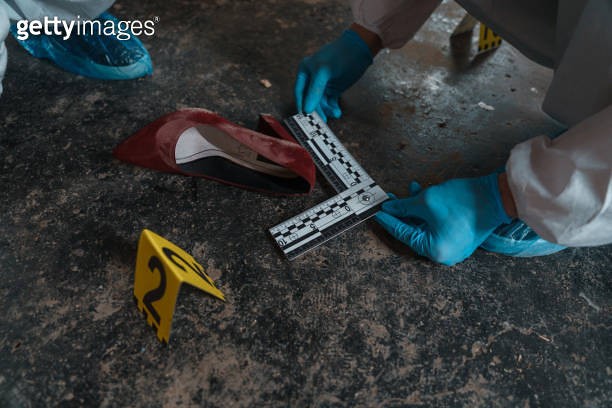 A forensic expert measuring a red shoe at the crime scene (1367836131 ...