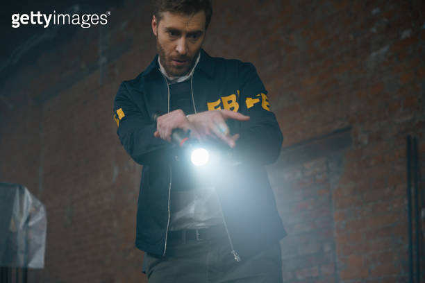 FBI agent with gun and flashlight at the crime scene looking down 이미지 ...
