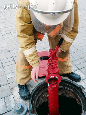 Firefighter or rescuer installs fire hydrant in open well. Fireman's ...