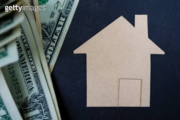 Brown paper house model with dollar banknotes on dark wooden table ...