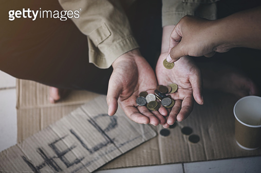 Closeup of men giving money to poor or homeless people poverty beggar in the city sitting on the ...