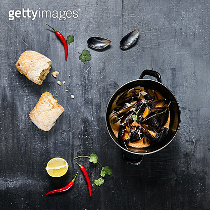 Mussel stew pot with creamy sauce, baguette on stone table. Mussels ...