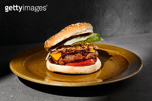 American burger with cheese and crispy onion on plate on gray concrete ...
