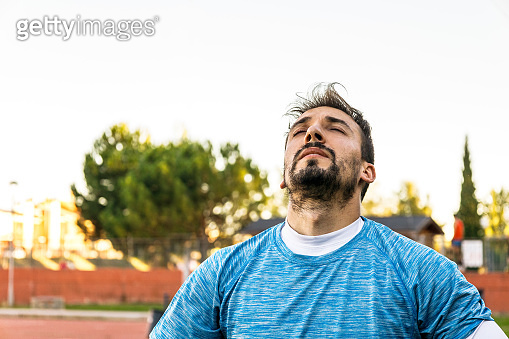 man catching air and breathing deeply after doing his workout outdoors ...
