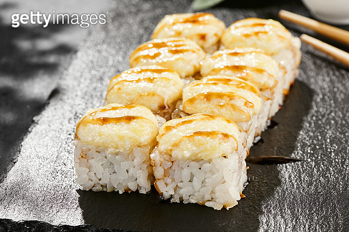 Baked Maki sushi on dark slate. Hot cheese maki with unagi sauce. Sushi ...