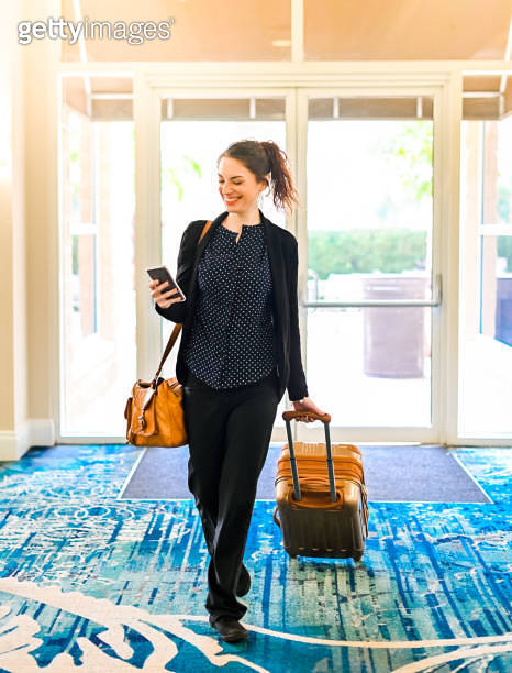 Professional businesswoman walks through a hotel lobby while on a ...