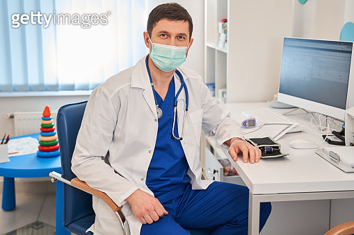 Confident general practitioner wearing protective mask is ready to work ...