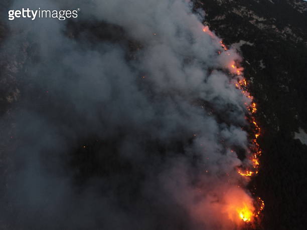 Aerial panoramic view of a forest fire at night, heavy smoke causes air ...