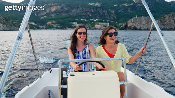 Female friends enjoying speedboat trip on a dream vacations. Looking at ...