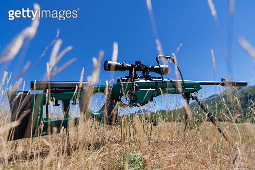 A green military sniper rifle with a scope for long distance tactical ...