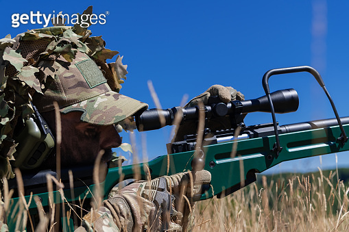 army soldier holding sniper rifle with scope and aiming in forest. war ...