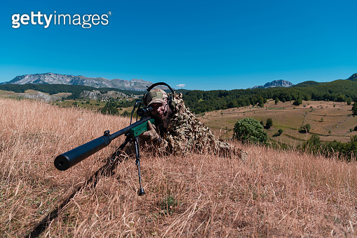 army soldier holding sniper rifle with scope and aiming in forest. war ...
